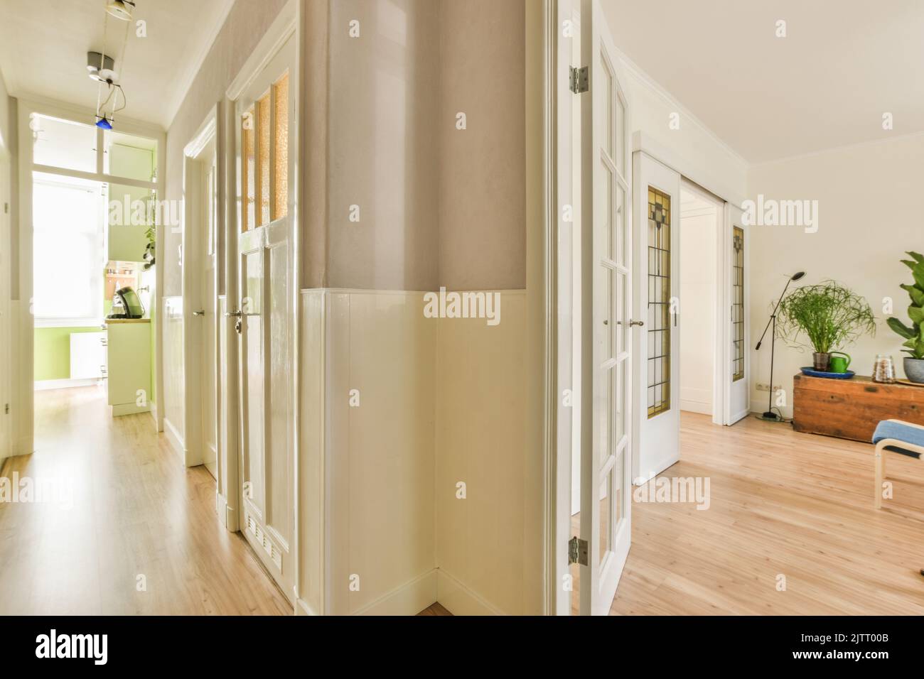 Narrow corridor with white walls and doors leading to spacious room ...