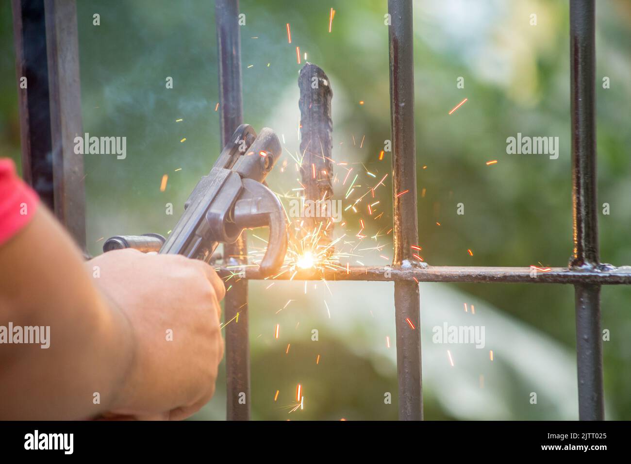 man using welding a piece of iron in an outdoor gate in Rio de Janeiro ...