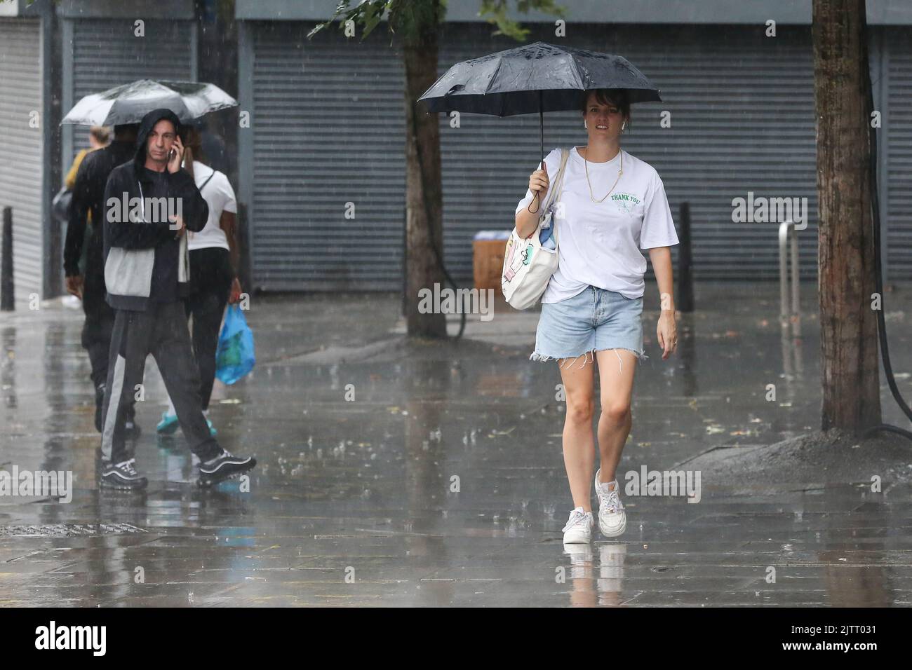 London, UK. 17th Aug, 2022. A woman shelters under an umbrella during ...