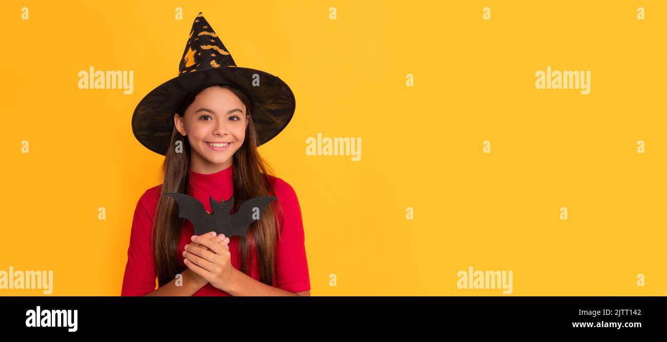 happy kid with bat wearing witch hat on yellow background, witchery ...