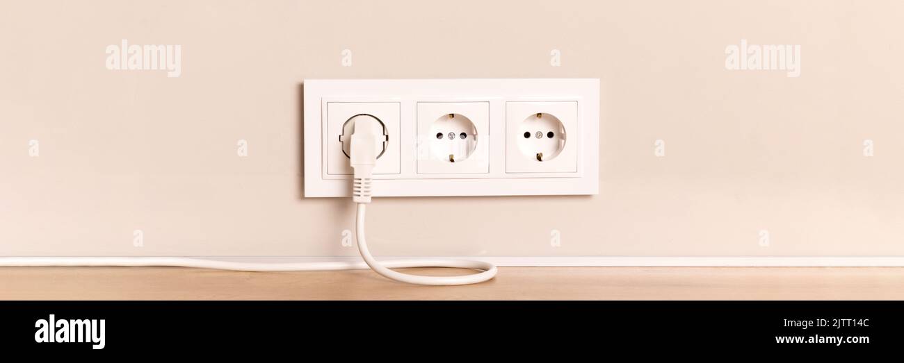 Group of white european electrical outlets with plug inserted into it ...