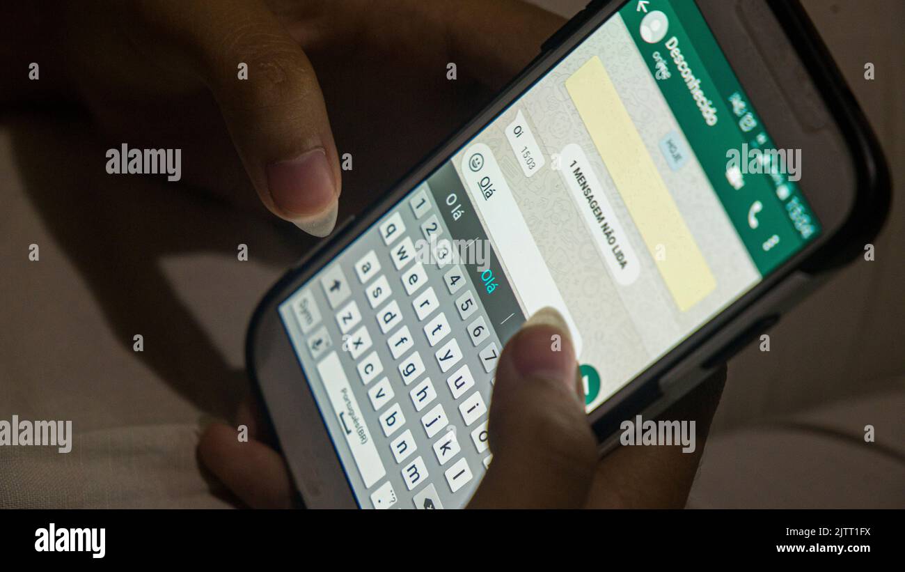 female hands typing a message in Portuguese ( hello ) in a messaging ...