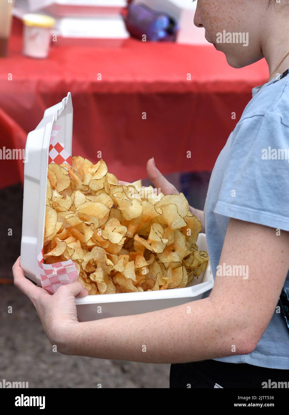 A young girl eats a serving of curly fries purchased from a food vendor ...