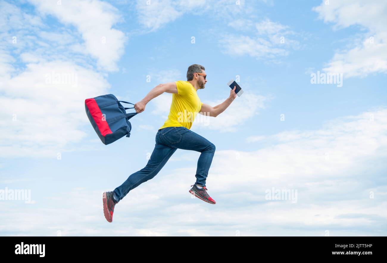 Energetic guy running with travel bag midair sky background, vacation ...