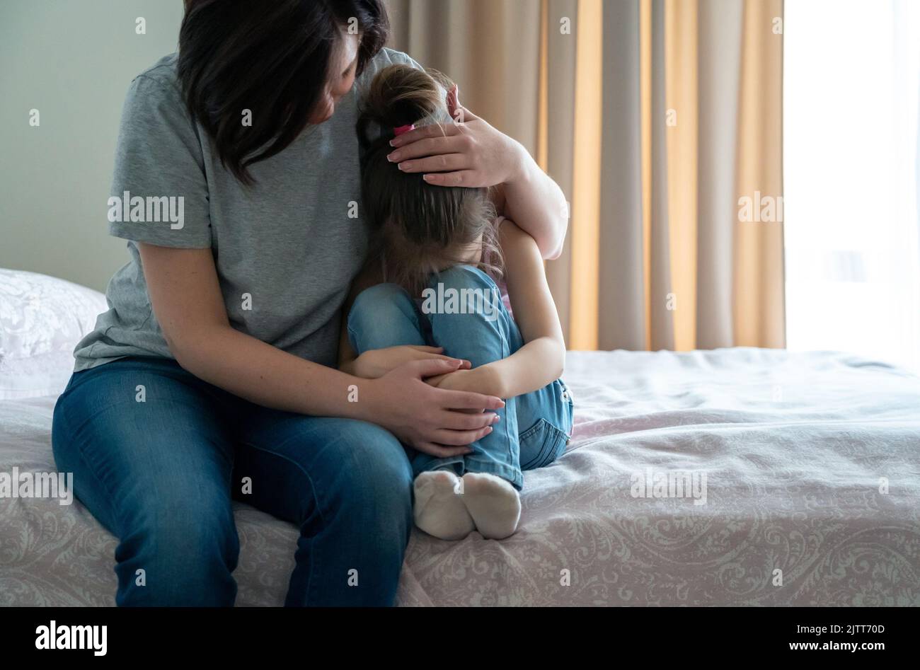 Loving young mother touching upset little daughter, expressing support, young mum comforting ...