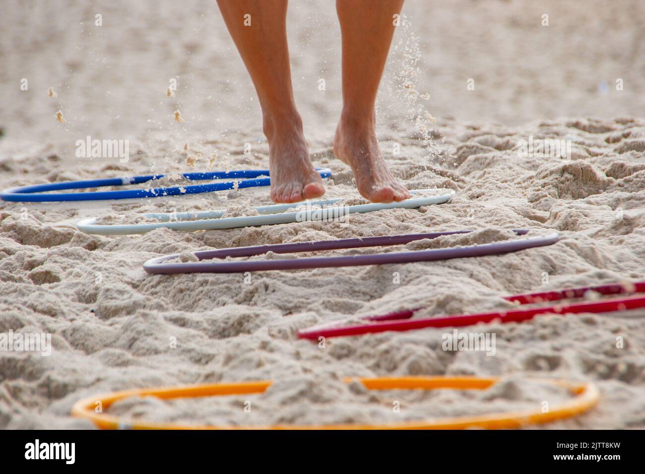 feet doing exercises on a functional exercise ladder on the beach sand ...