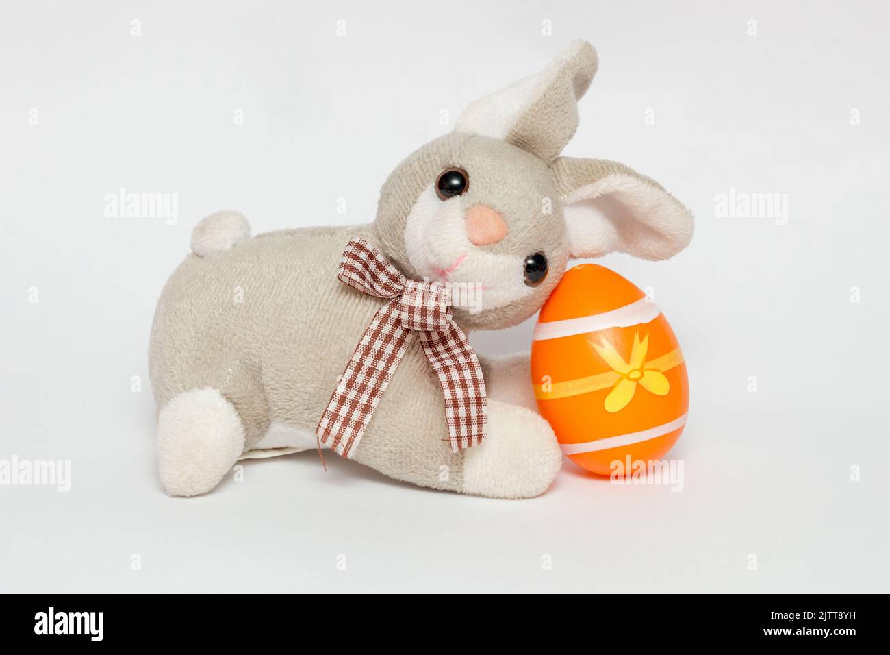 gray plush rabbit with small orange plastic egg, used for Easter ...