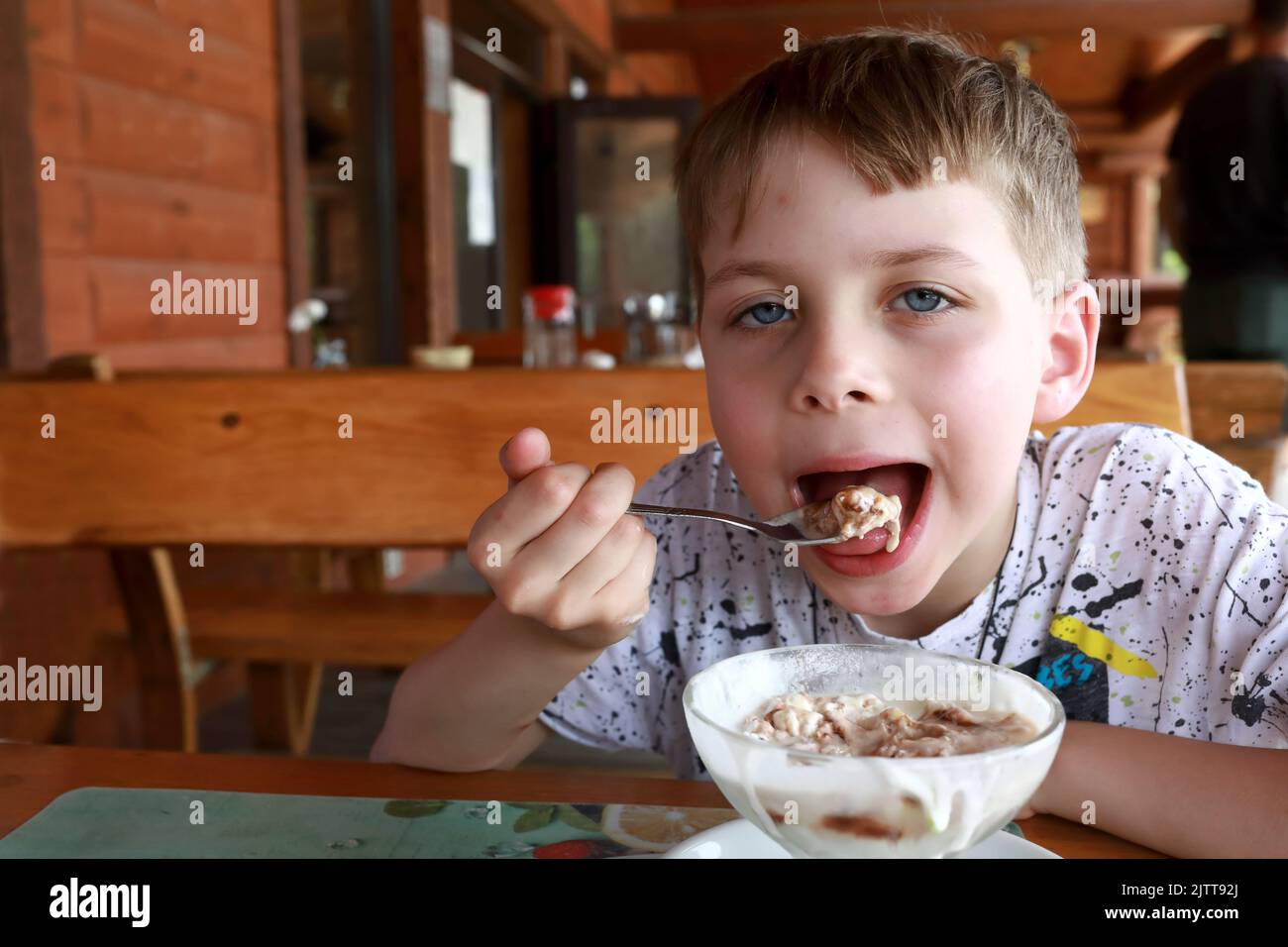 Boy eating ice-cream at table in restaurant Stock Photo - Alamy