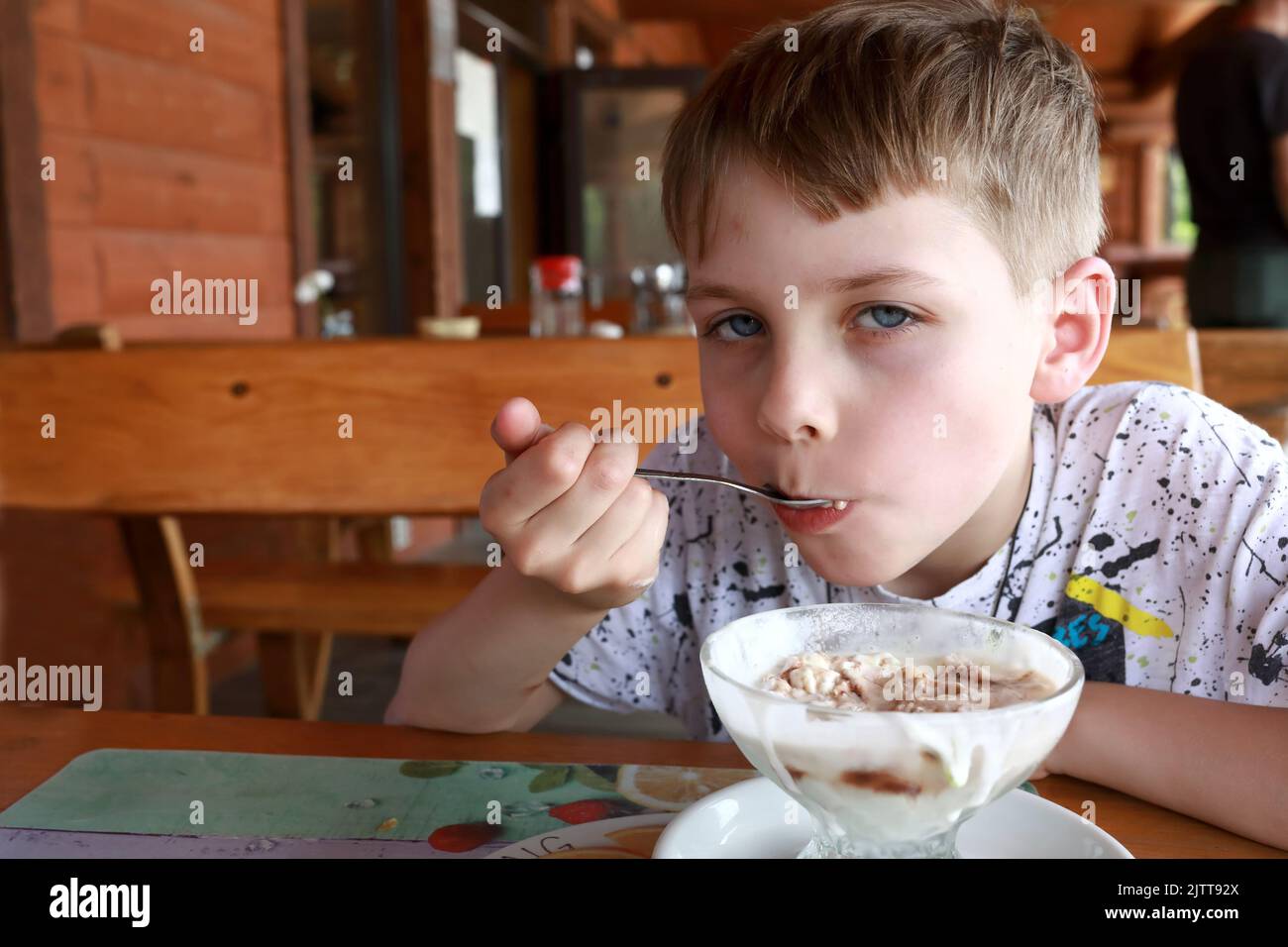 Kid eating ice-cream at table in restaurant Stock Photo - Alamy