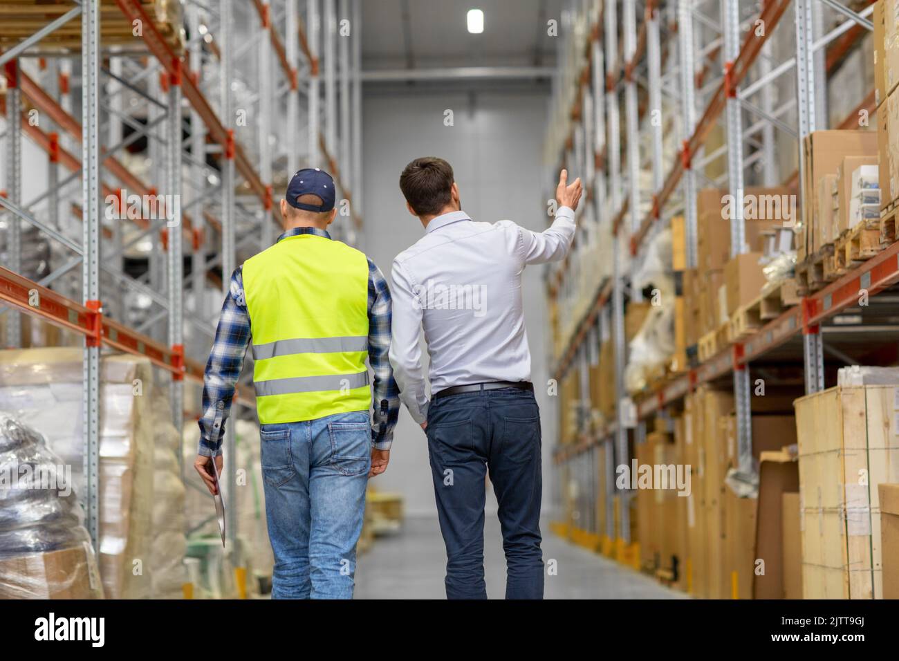 worker and businessman walking along warehouse Stock Photo - Alamy