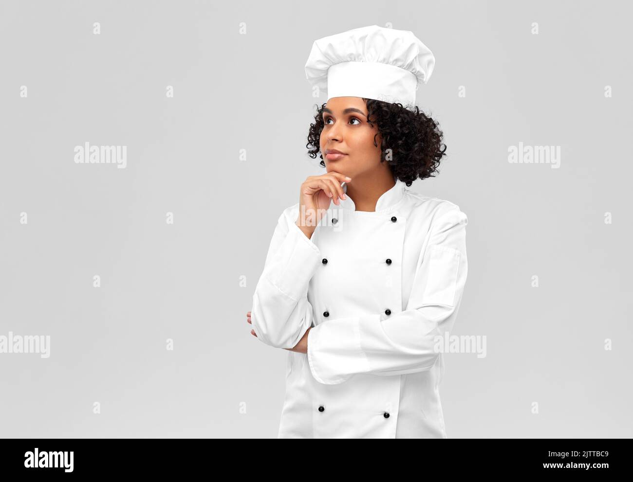 thinking female chef over grey background Stock Photo - Alamy
