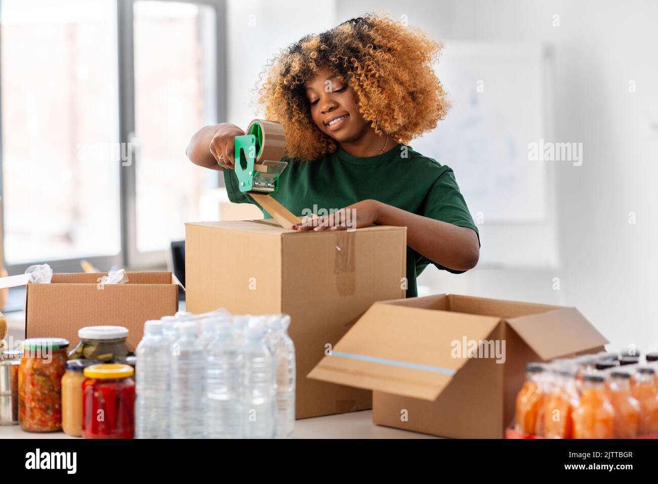 volunteer woman packing food in donation boxes Stock Photo - Alamy