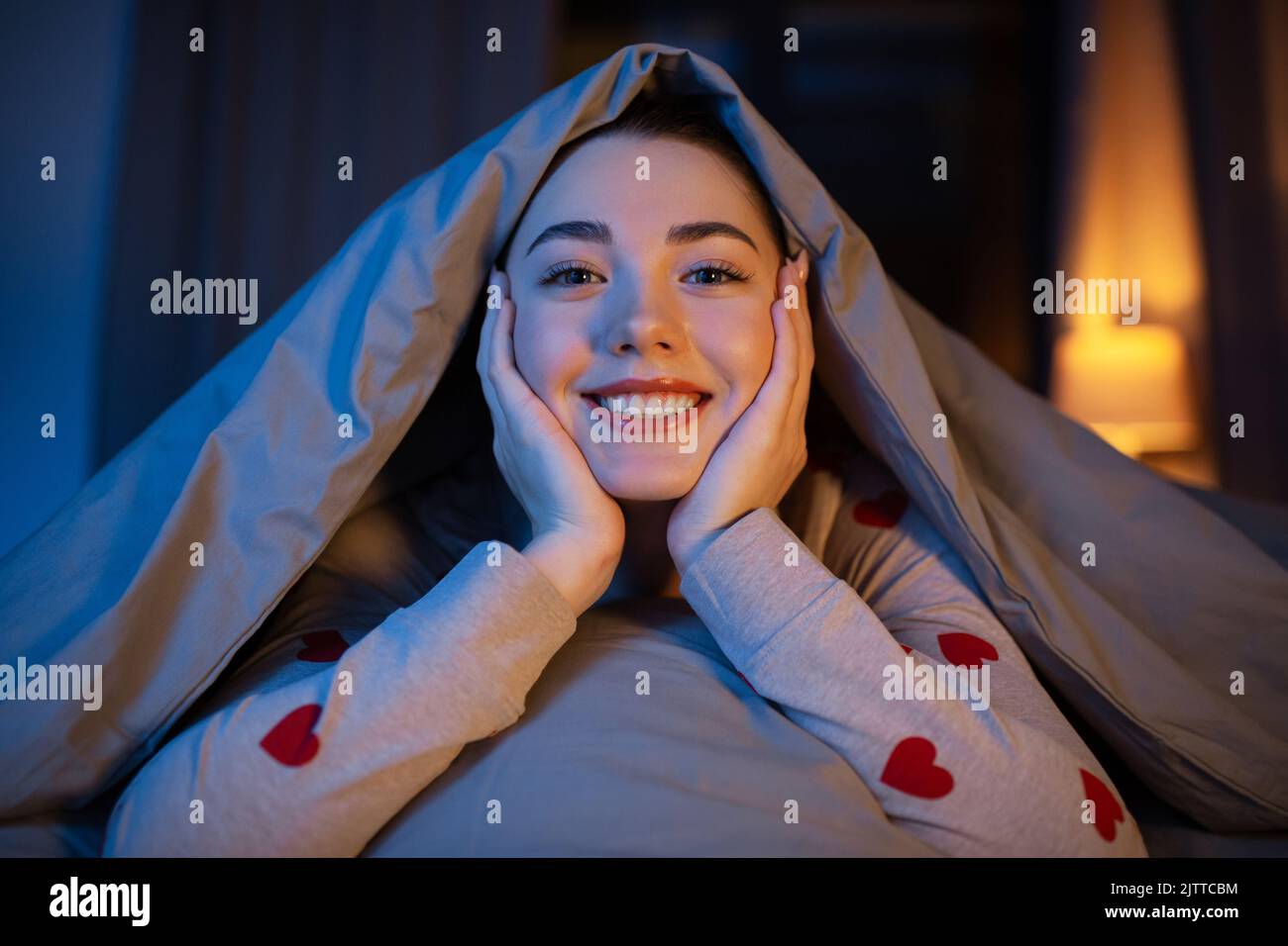 happy teenage girl lying under blanket in bed Stock Photo - Alamy