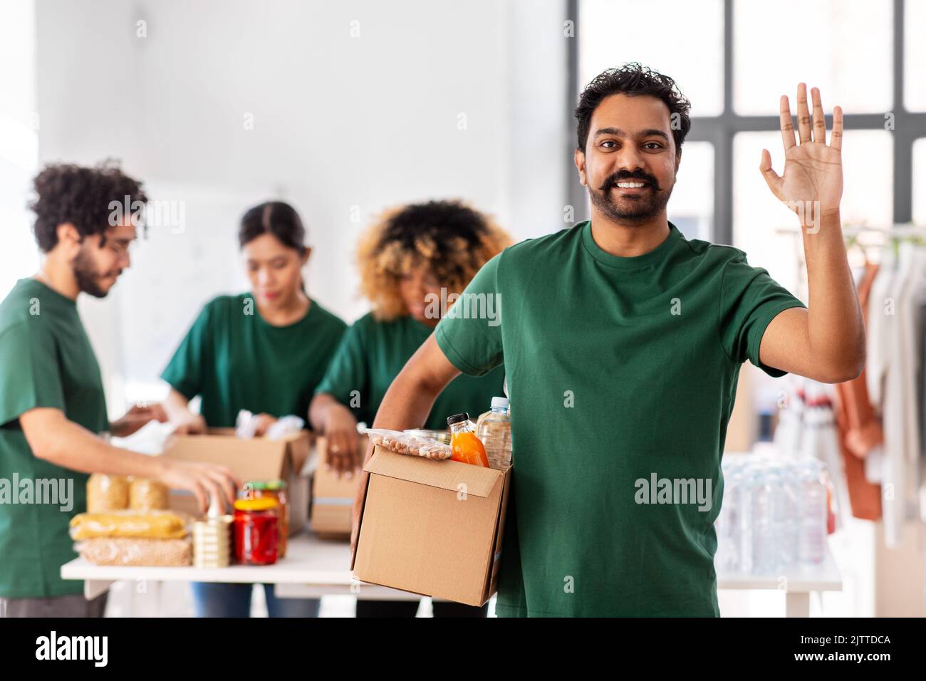 male volunteer with food in box waving hand Stock Photo - Alamy