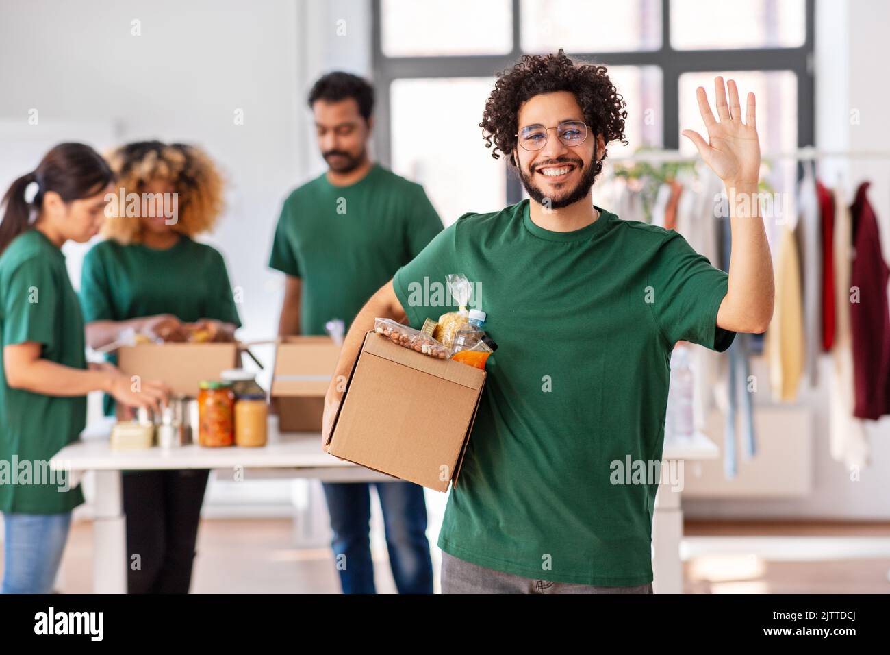 male volunteer with food in box waving hand Stock Photo - Alamy