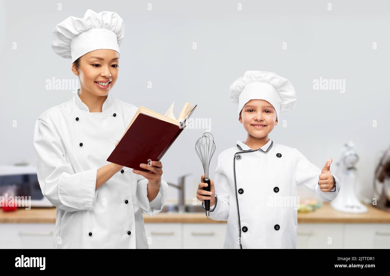female chef with cook book and girl in kitchen Stock Photo - Alamy