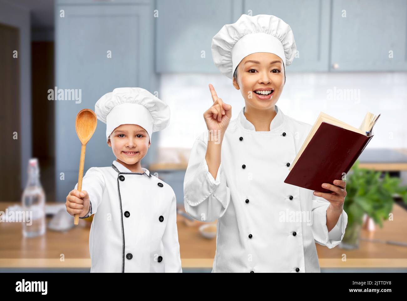 female chef with cook book and girl in kitchen Stock Photo - Alamy
