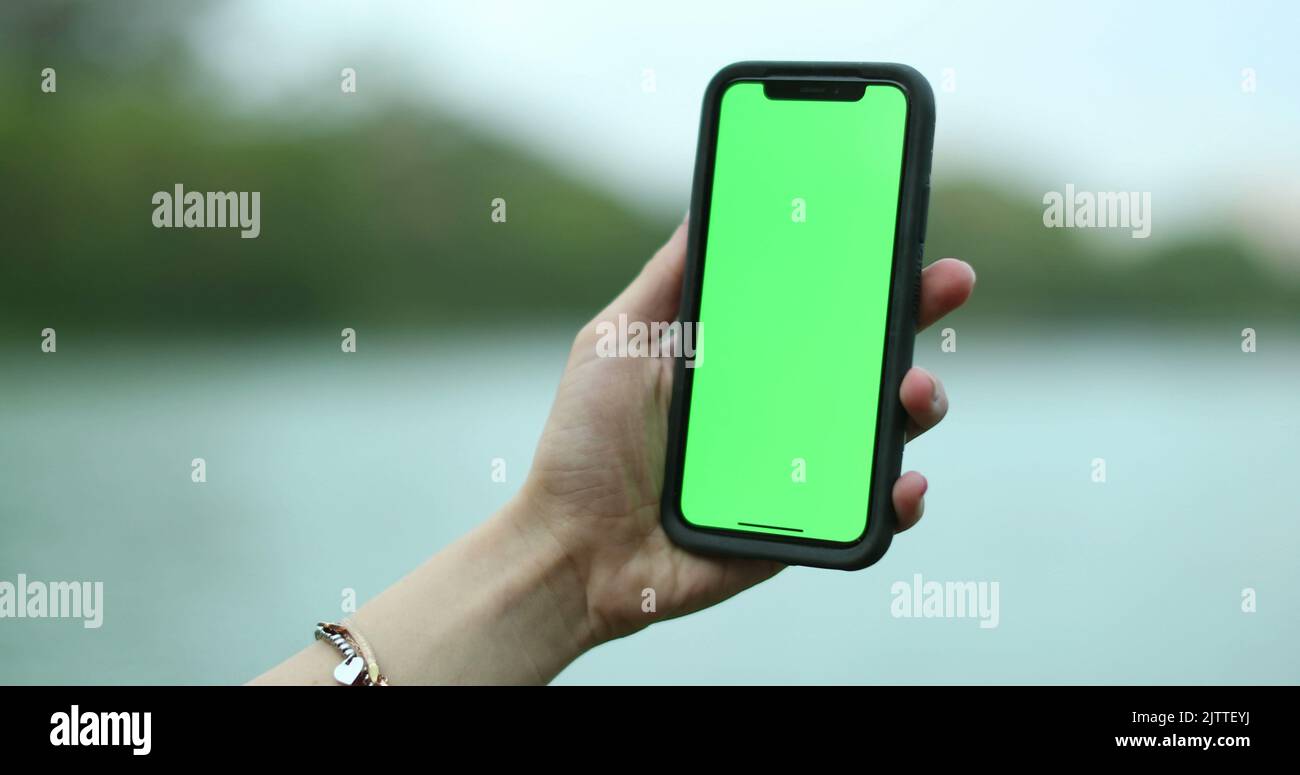 Female hand holding cellphone with green screen. Girl using mobile ...