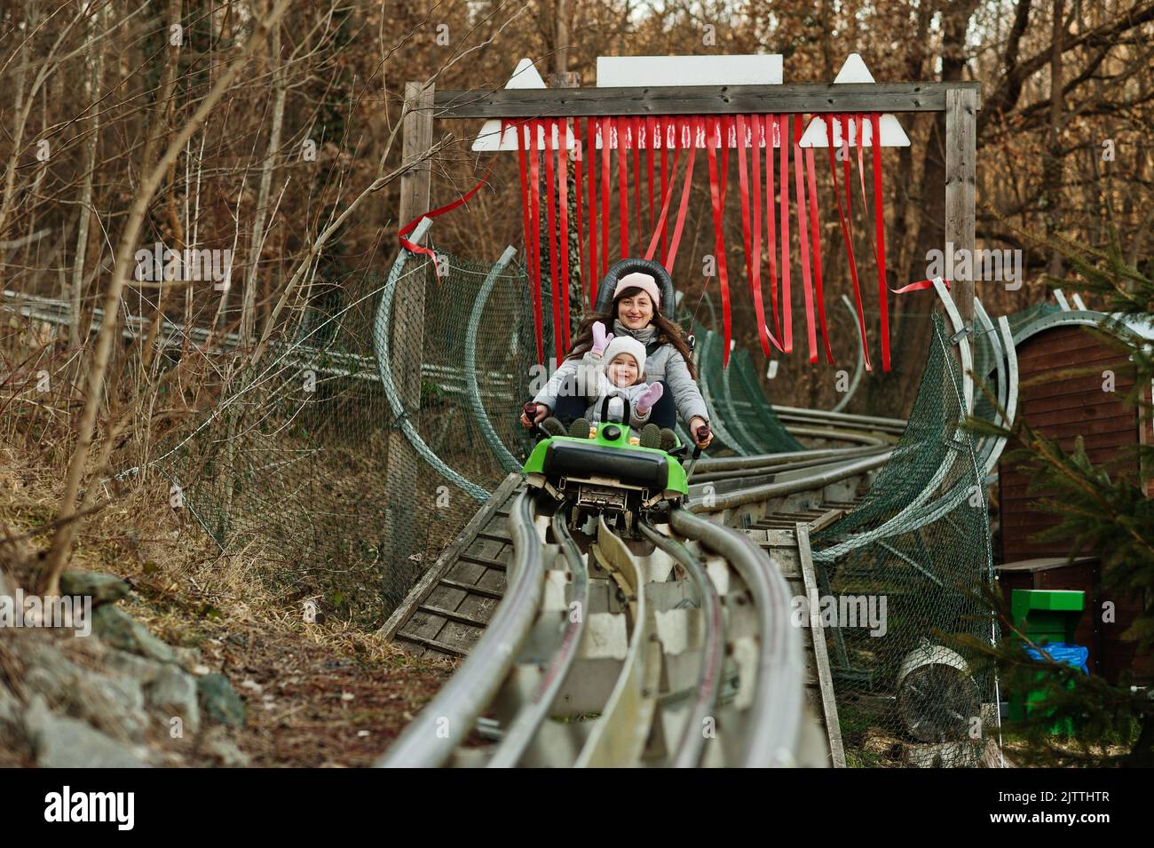 Mother with daughter ride electric sleigh on rails Stock Photo - Alamy