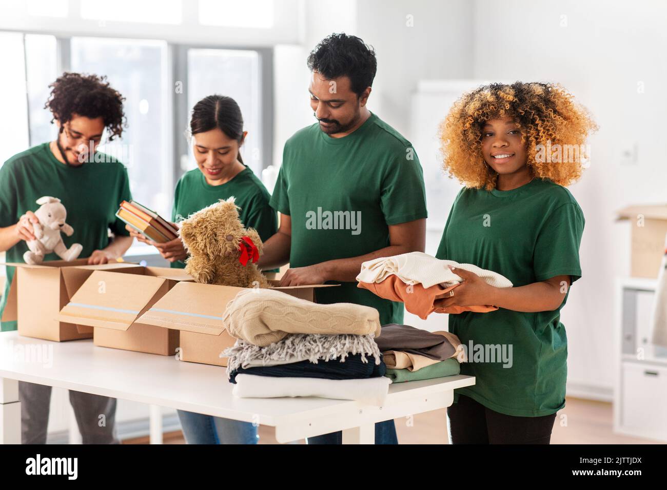 happy volunteers packing stuff in donation boxes Stock Photo - Alamy