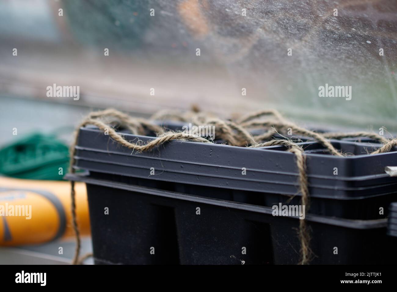 A rope on empty black containers for plant seedlings on windowsill by ...