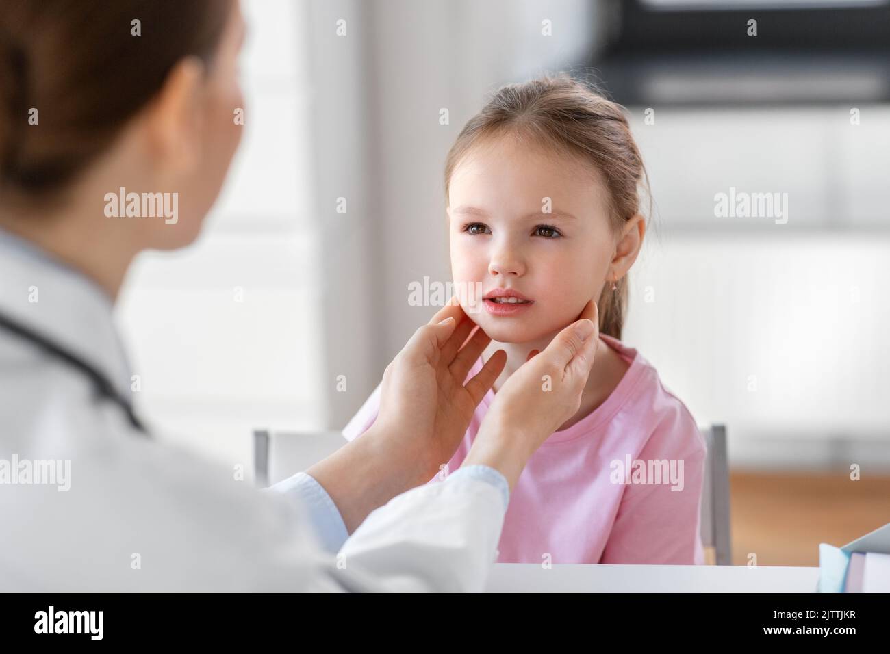 doctor checking girl patient's tonsils at clinic Stock Photo - Alamy