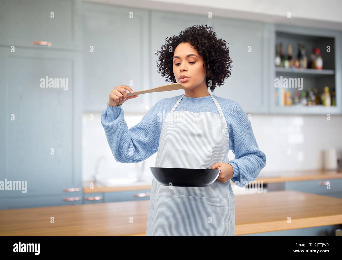 woman with frying pan tasting food in kitchen Stock Photo - Alamy