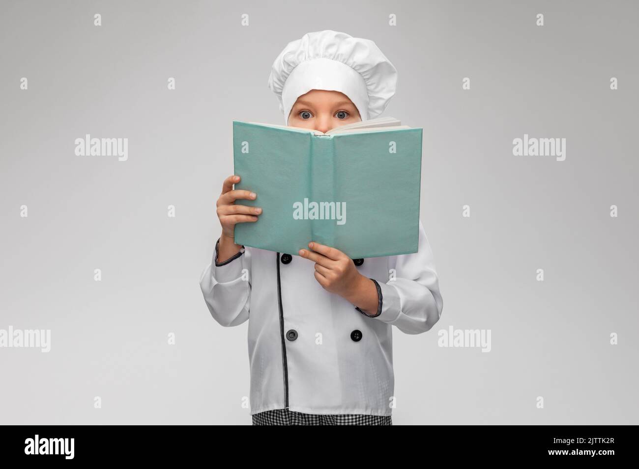little girl in chef's toque reading cook book Stock Photo - Alamy
