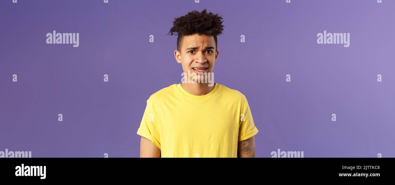 Close-up portrait of awkward and embarrassed young hispanic guy looking ...