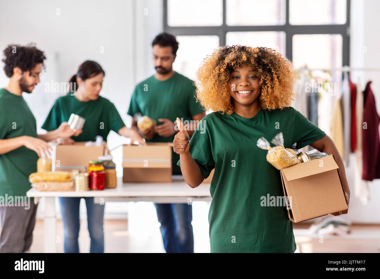 female volunteer with food in box shows thumbs up Stock Photo - Alamy