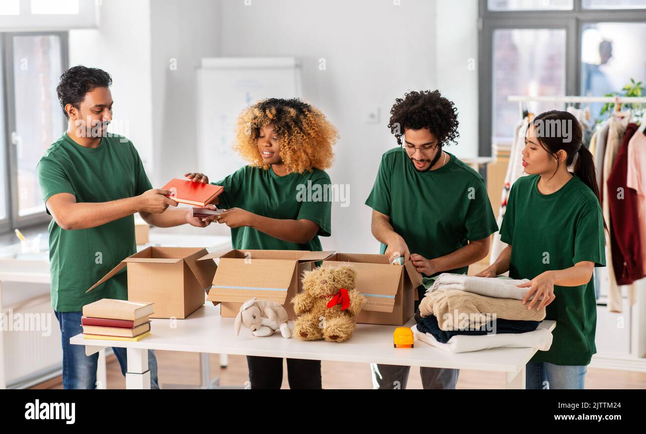 happy volunteers packing stuff in donation boxes Stock Photo - Alamy