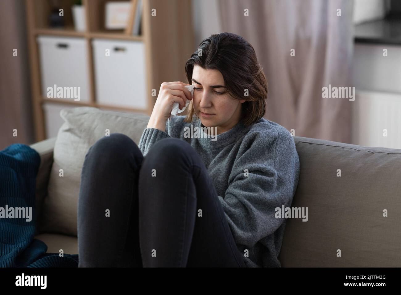 sad crying woman sitting on sofa at home Stock Photo - Alamy