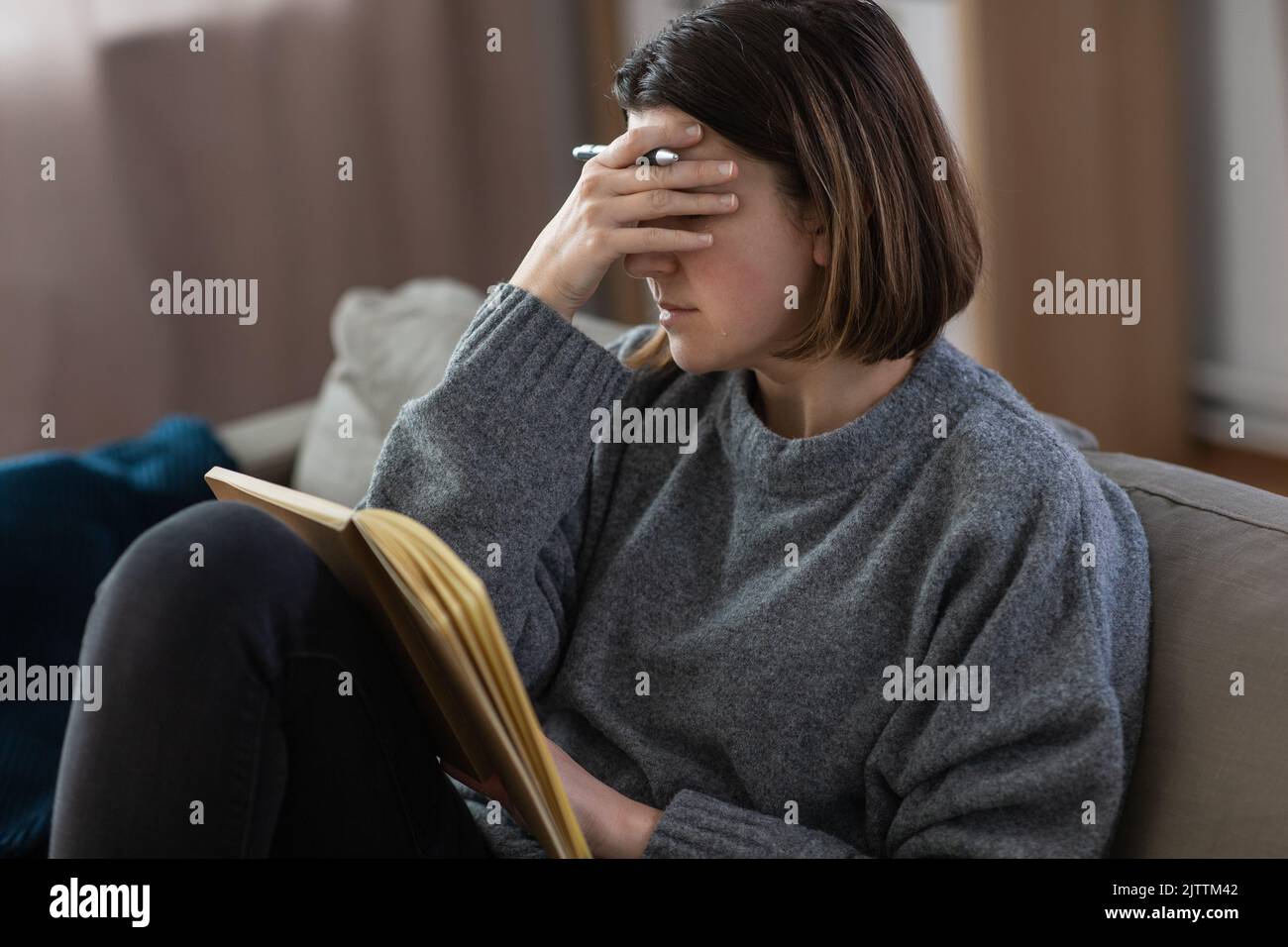 crying woman with diary sitting on sofa at home Stock Photo - Alamy