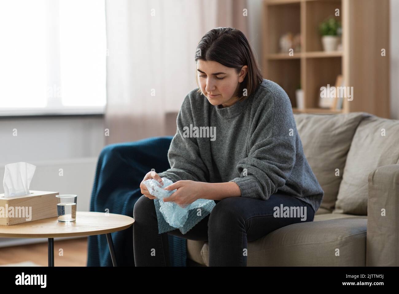 sad woman popping bubble wrap at home Stock Photo - Alamy