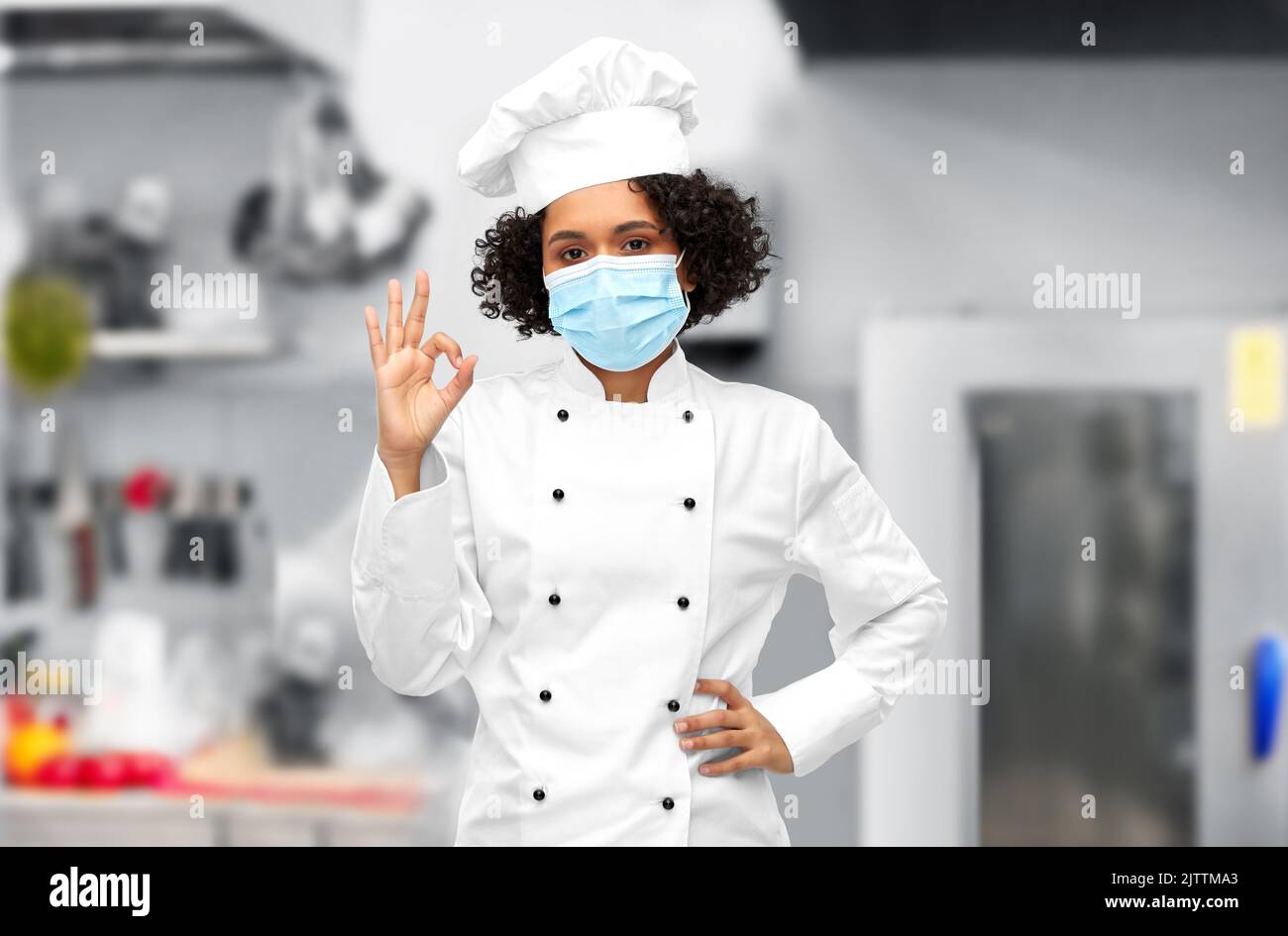female chef in medical mask and toque showing ok Stock Photo - Alamy