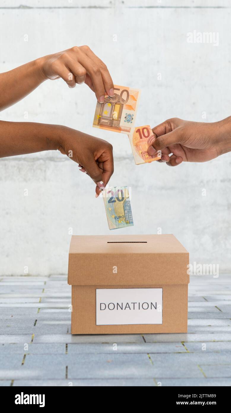 hands putting money into donation box on street Stock Photo - Alamy