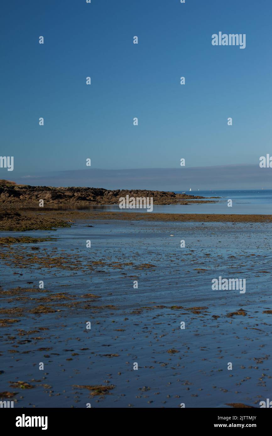 The carved rocks plunge into the blue sea. Offshore, boats sail on the ...