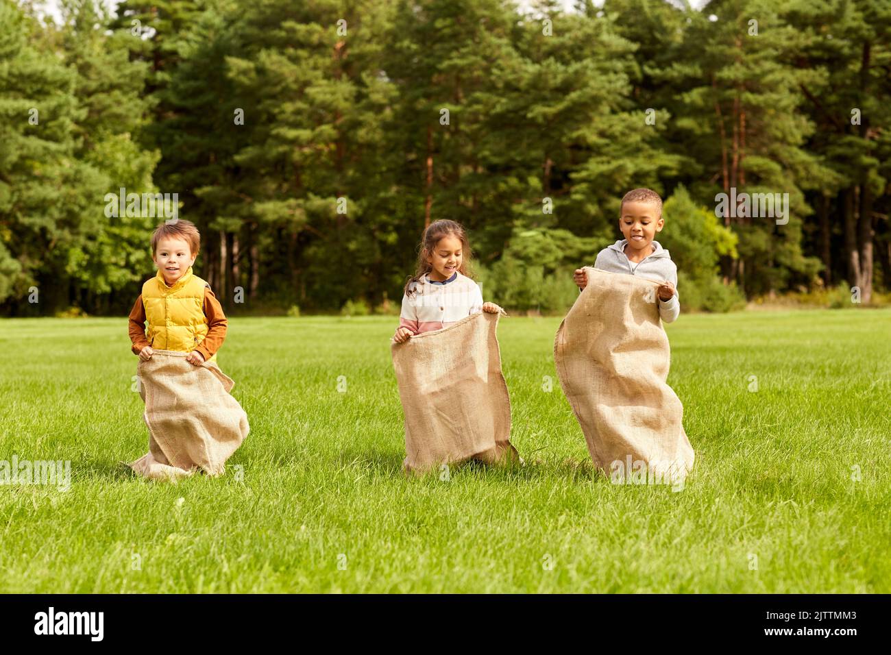 happy children playing bag jumping game at park Stock Photo - Alamy