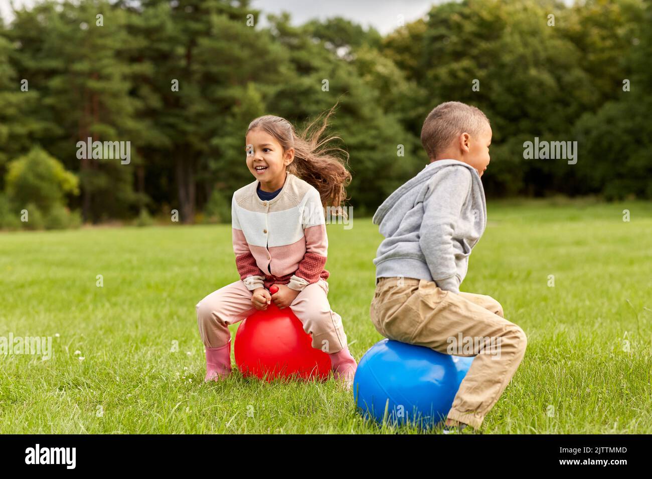happy children bouncing on hopper balls at park Stock Photo - Alamy