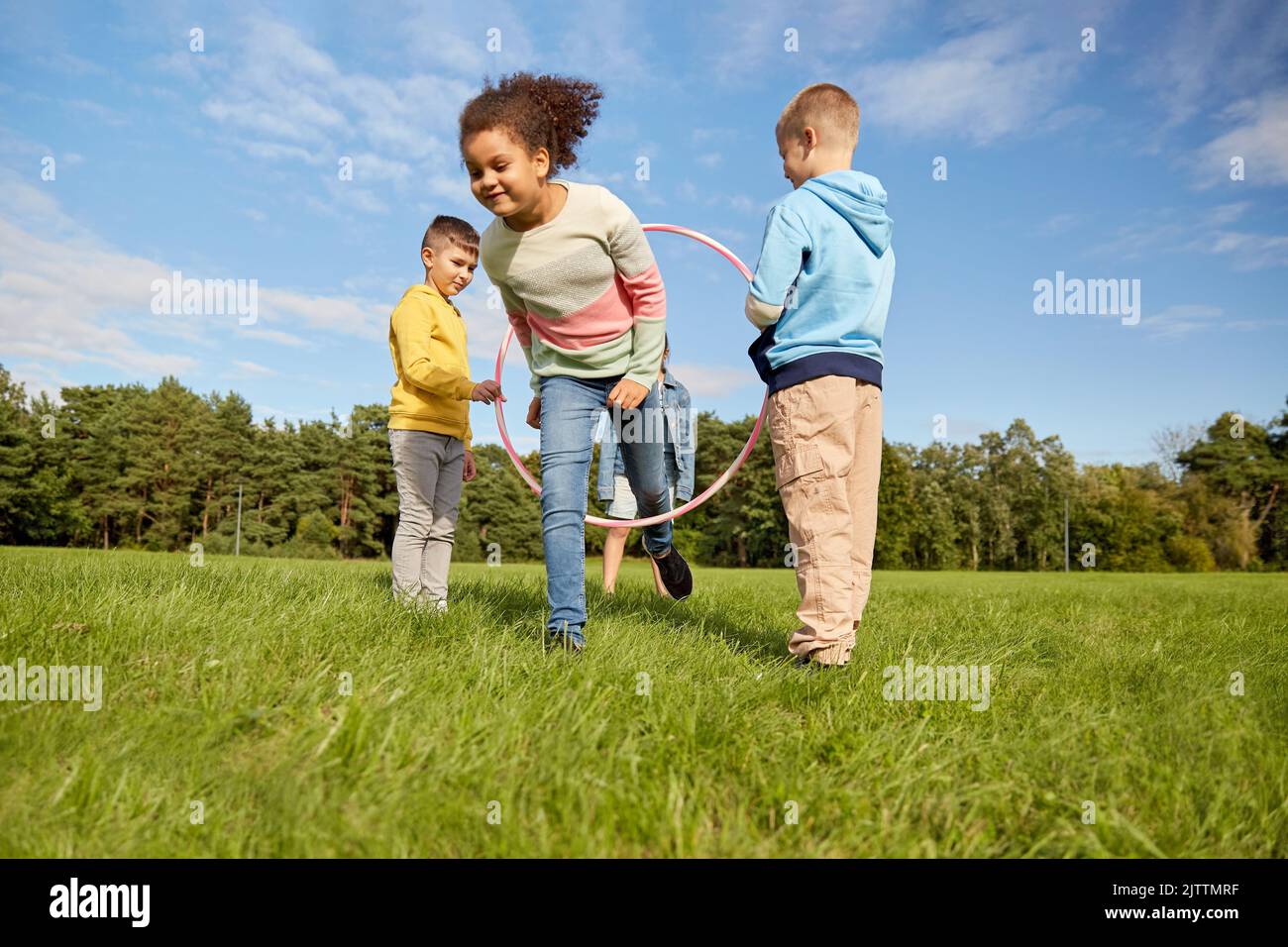 happy children playing game with hula hoop at park Stock Photo - Alamy