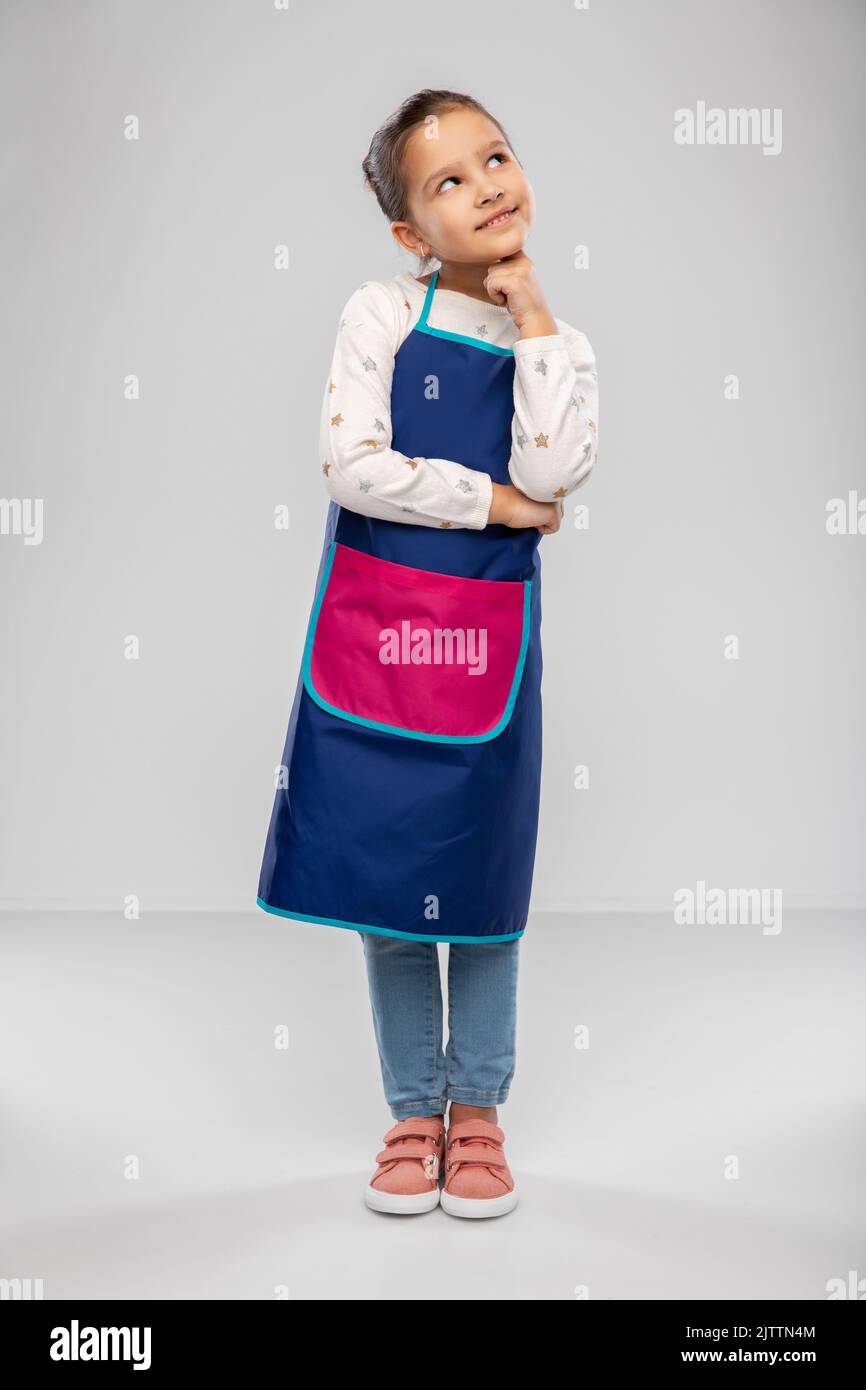 thinking little girl in kitchen apron Stock Photo - Alamy