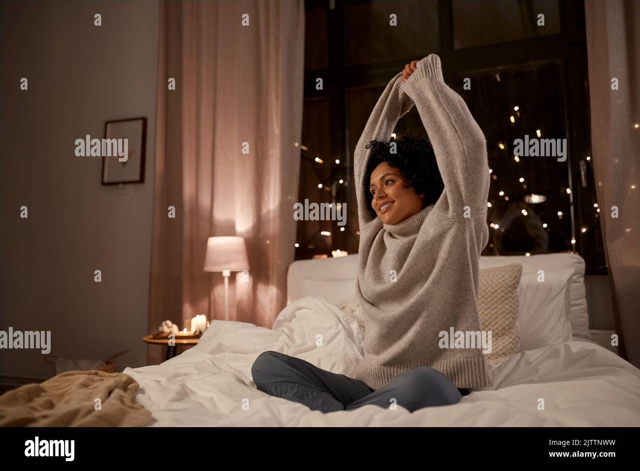 woman in sweater stretching in bed at night Stock Photo - Alamy