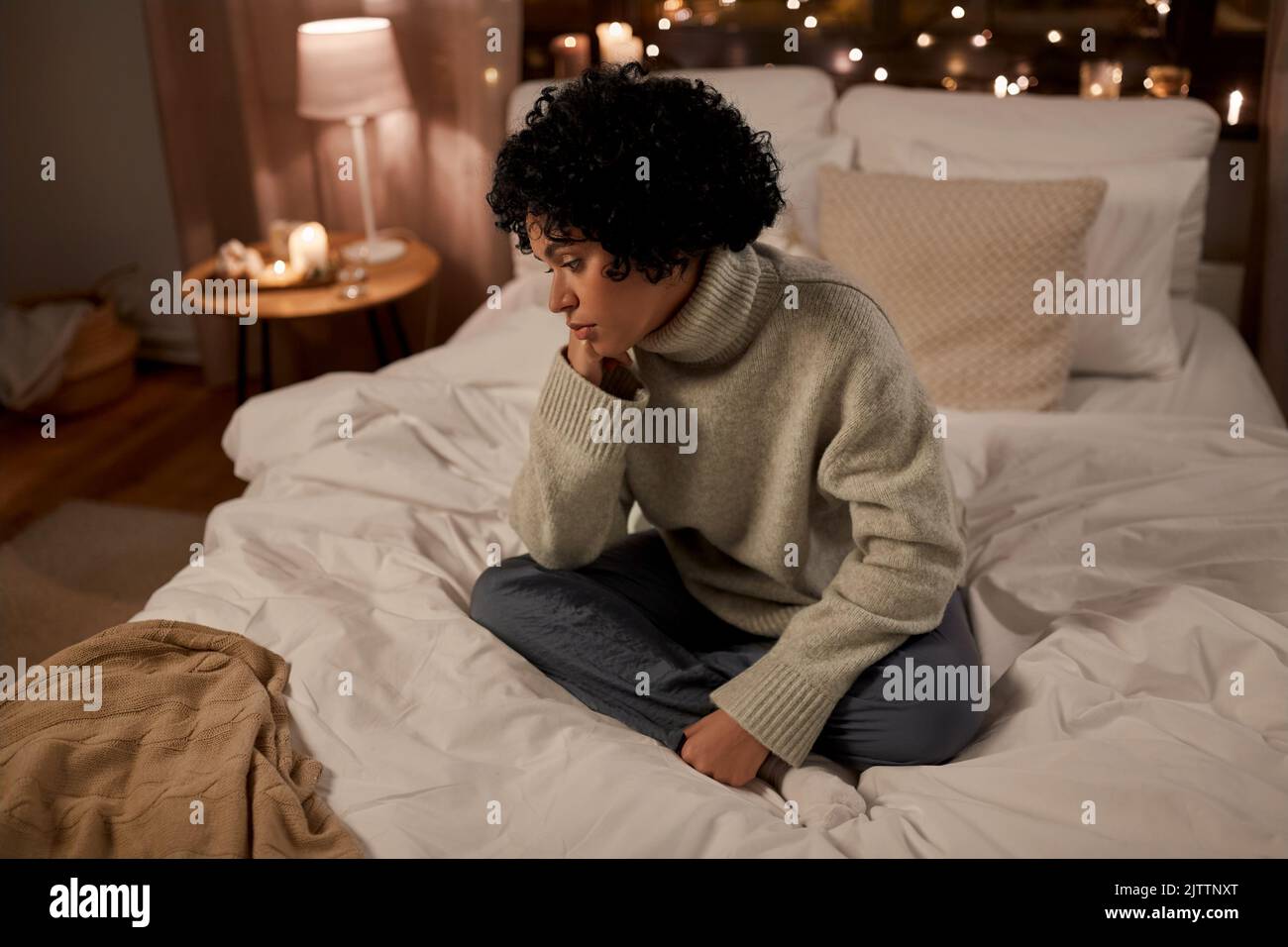 sad woman in sweater on bed at home at night Stock Photo - Alamy