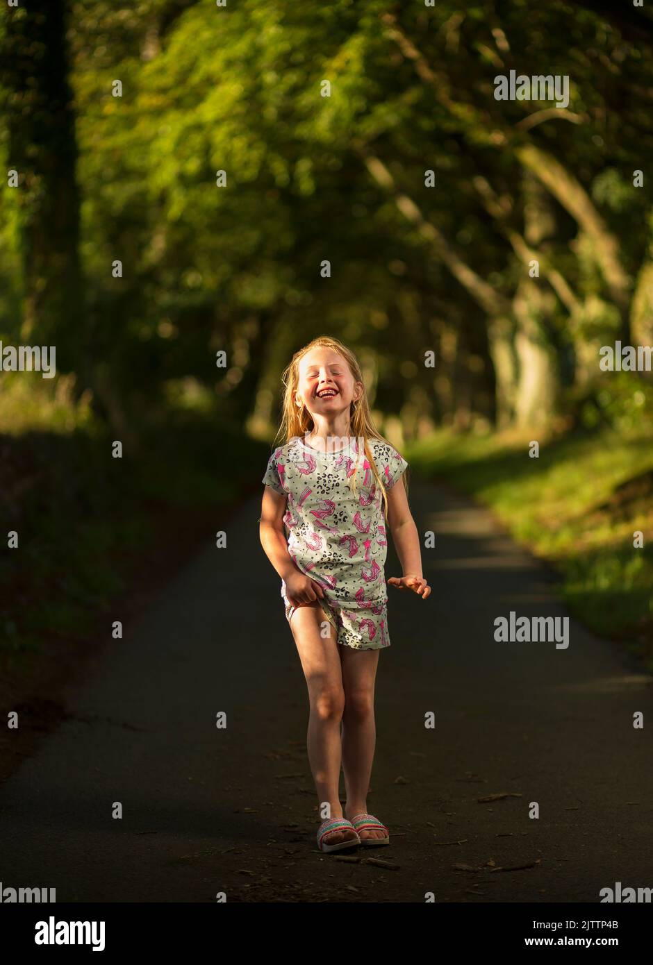 Young Caucasian girl walking and laughing on a path in the countryside ...