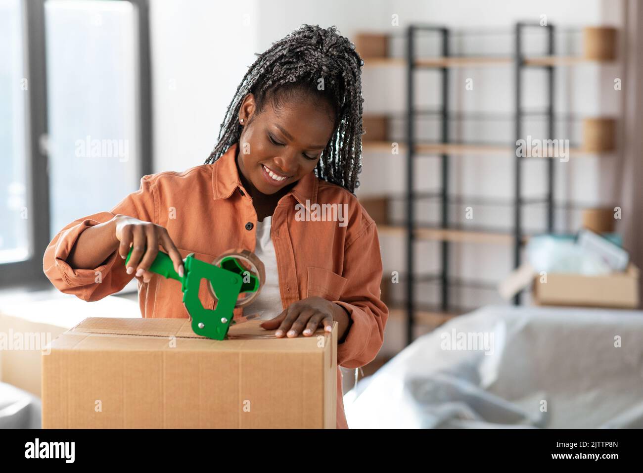 woman with adhesive tape packing box at new home Stock Photo - Alamy