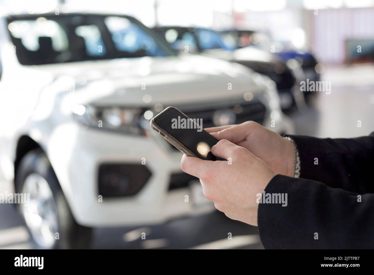 Salesman using mobile smart phone at dealer showroom. Modern working ...