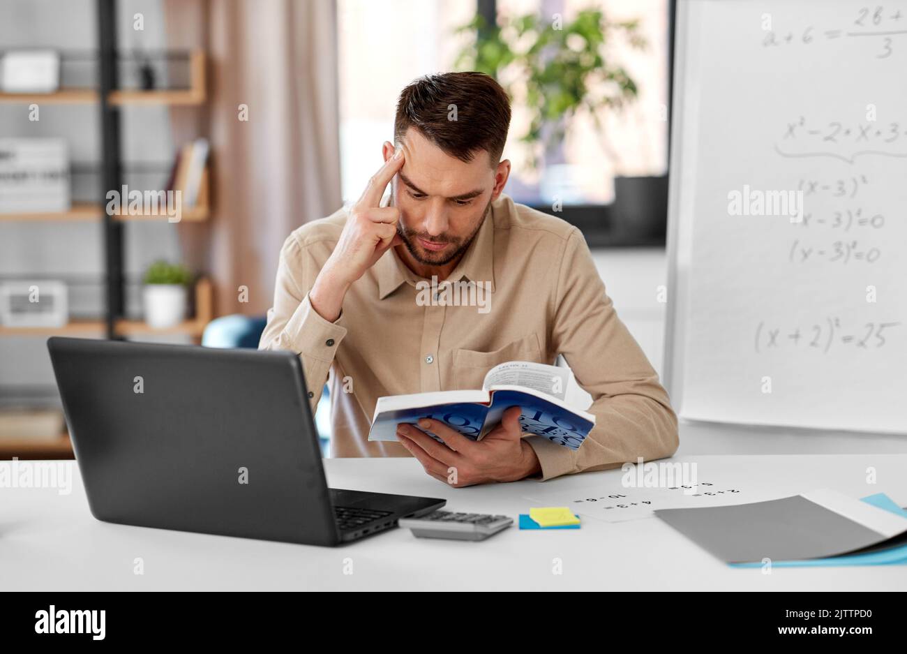 math teacher with laptop and book at home office Stock Photo - Alamy