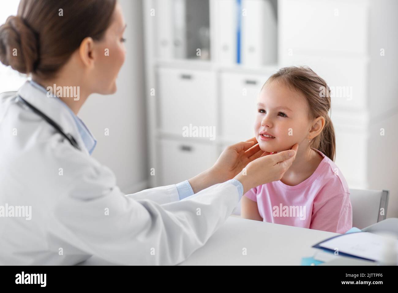 doctor checking girl patient's tonsils at clinic Stock Photo - Alamy