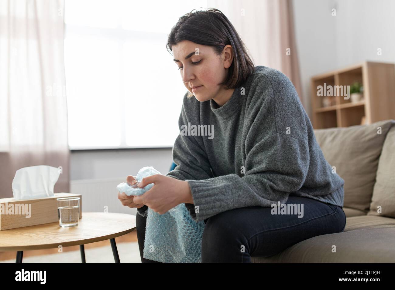 sad woman popping bubble wrap at home Stock Photo - Alamy