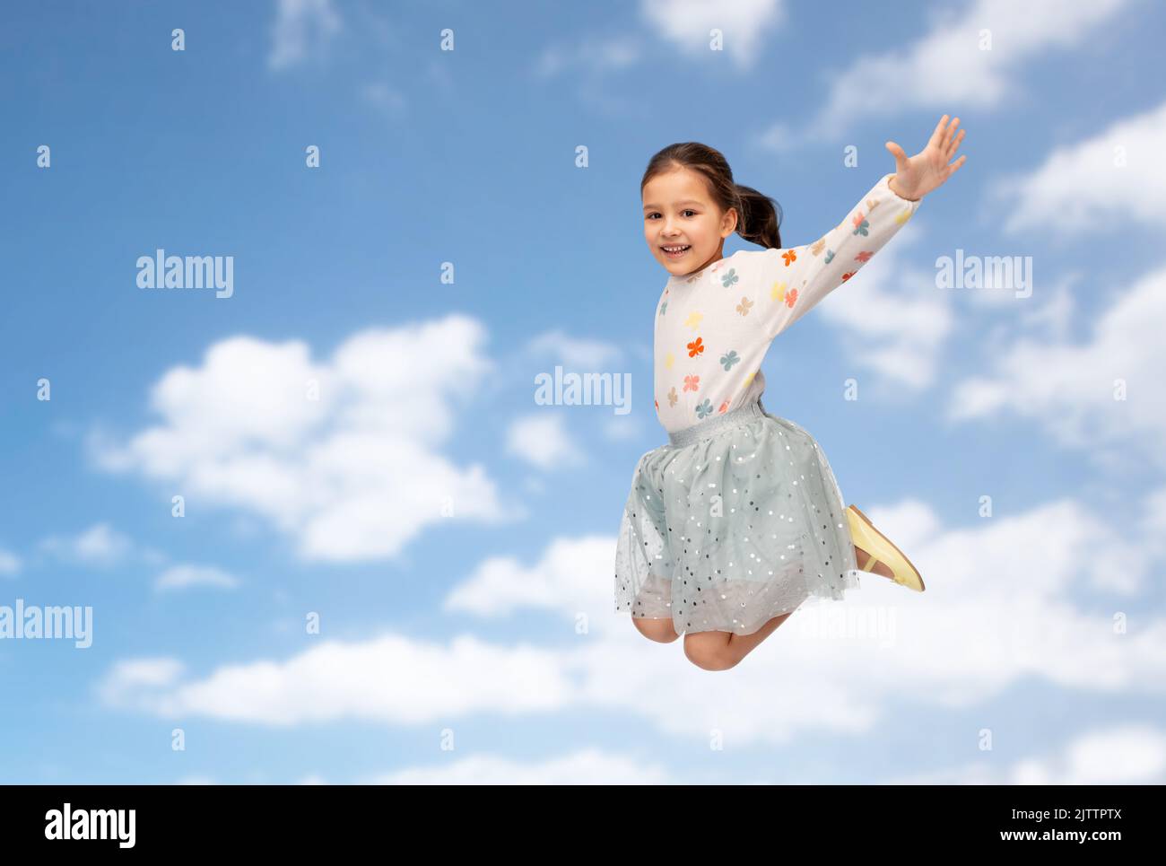 happy little girl jumping over blue sky and clouds Stock Photo - Alamy